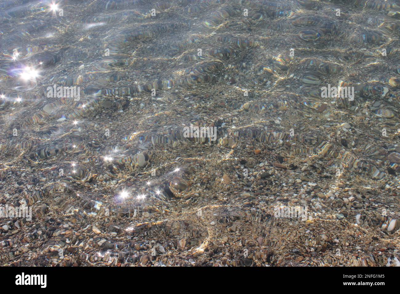 rippled transparent water surface with reflections of the sun shining ...