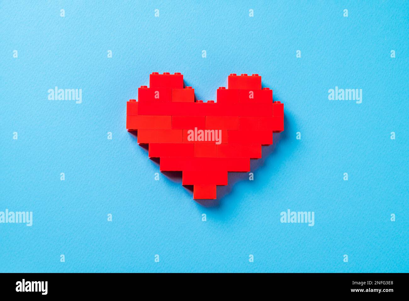 Red heart made of plastic bricks on a blue background Stock Photo - Alamy