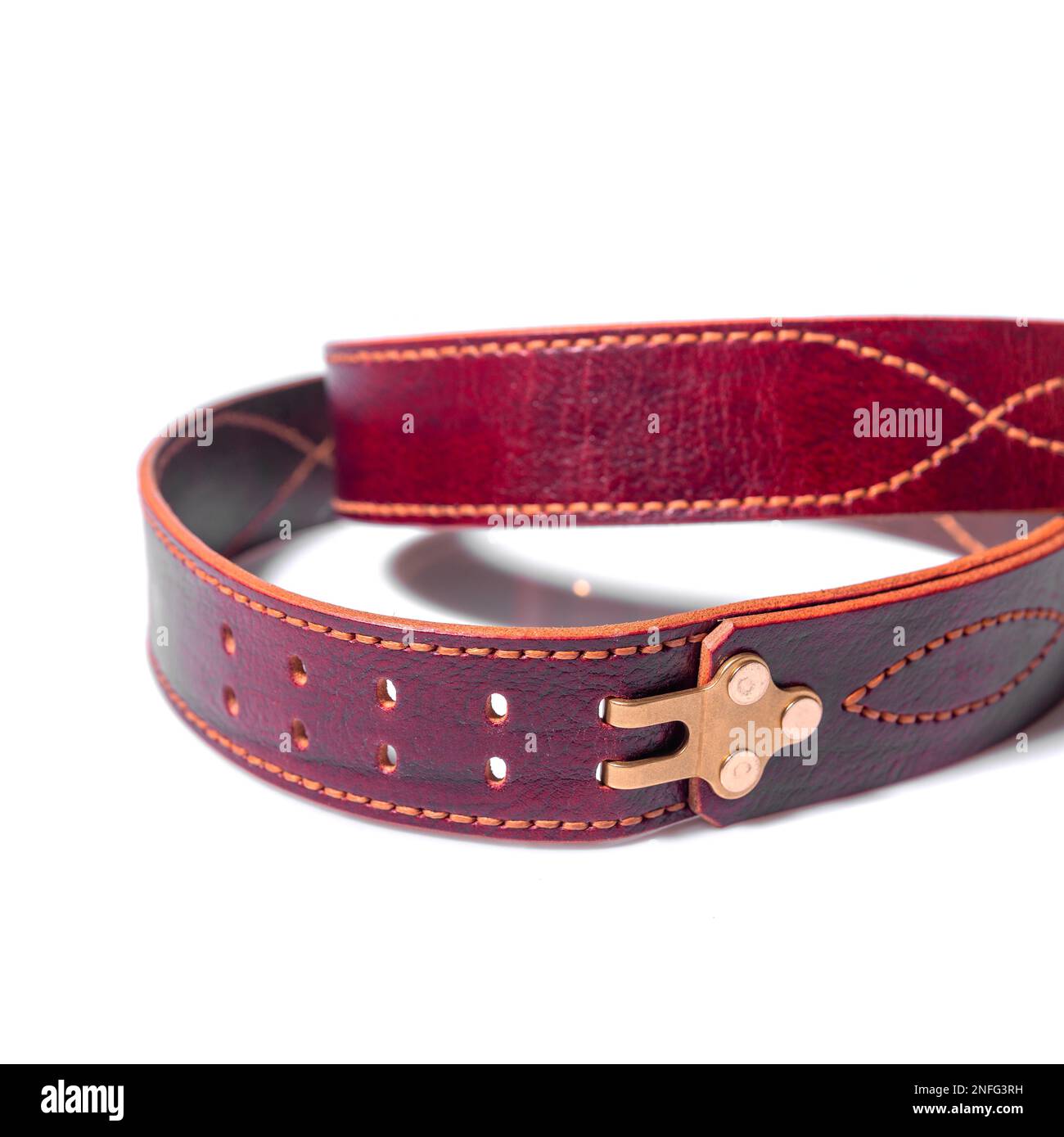 A rolled-up brown leather belt with a metal buckle on a white ...