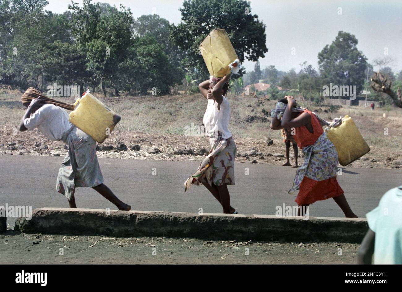 Rwandan refugees carry jerrycans of purified water treated by the U.S ...