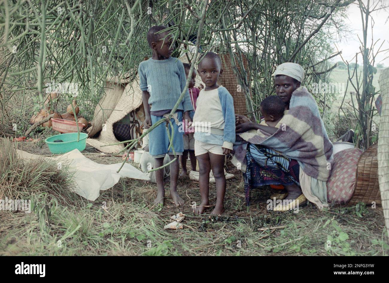 A Rwandan woman refugee with her children, sits next to her straw mat ...