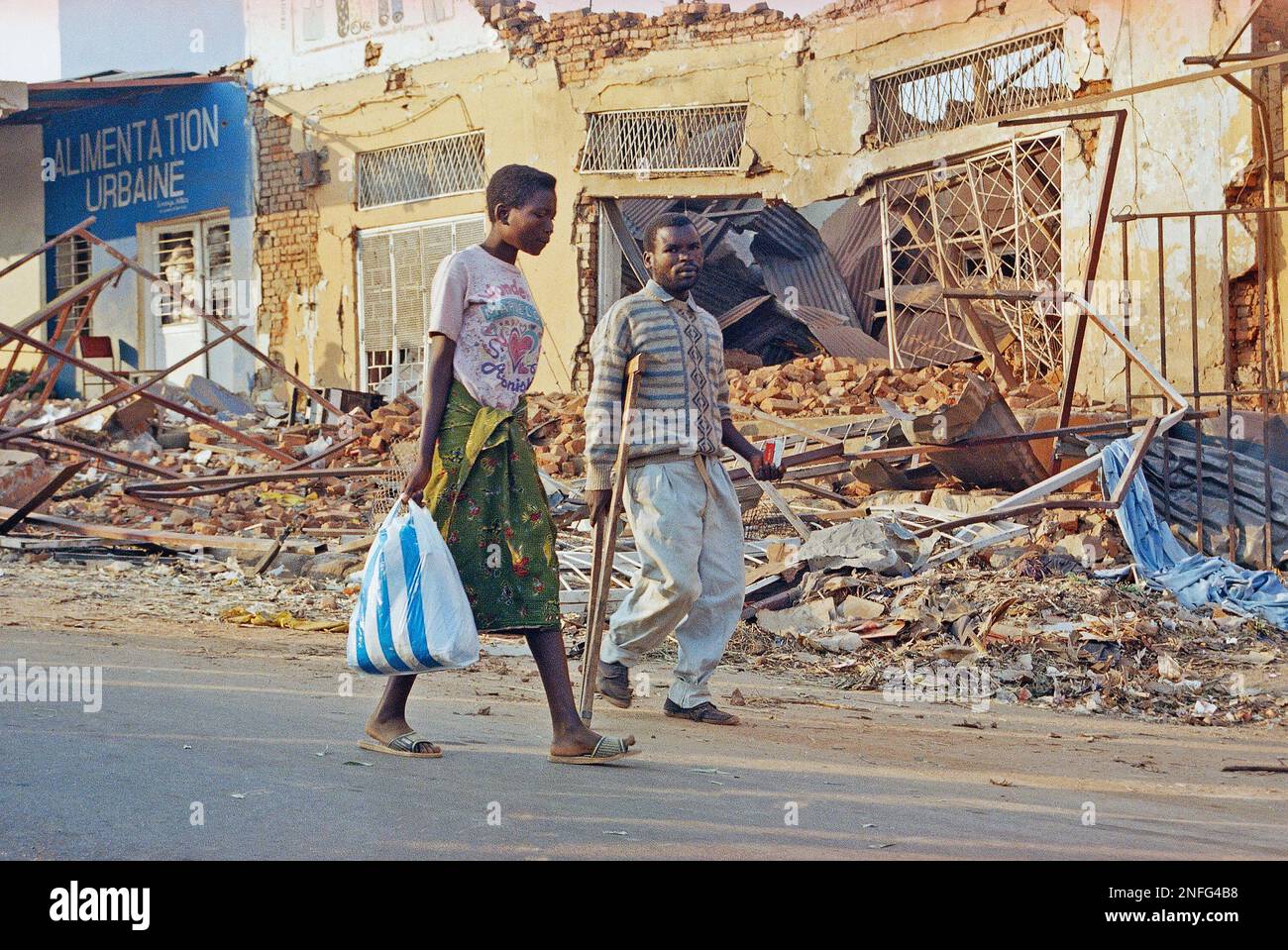 Kigali residents walk past debris in the city center, Wednesday, August ...