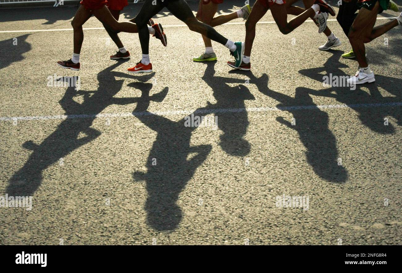 Competitors cast shadows during the men's marathon, the last event of ...