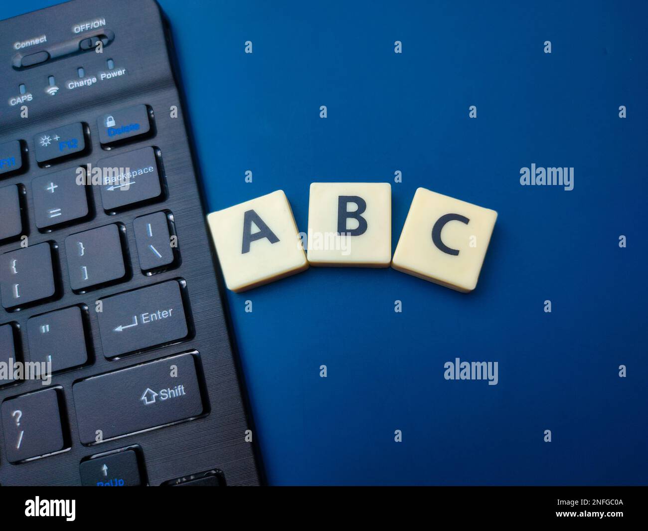 Black keyboard and toy word with the word ABC on blue background ...