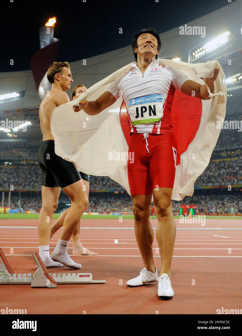 Japanese sprinter Nobuharu Asahara celebrates with a national flag ...
