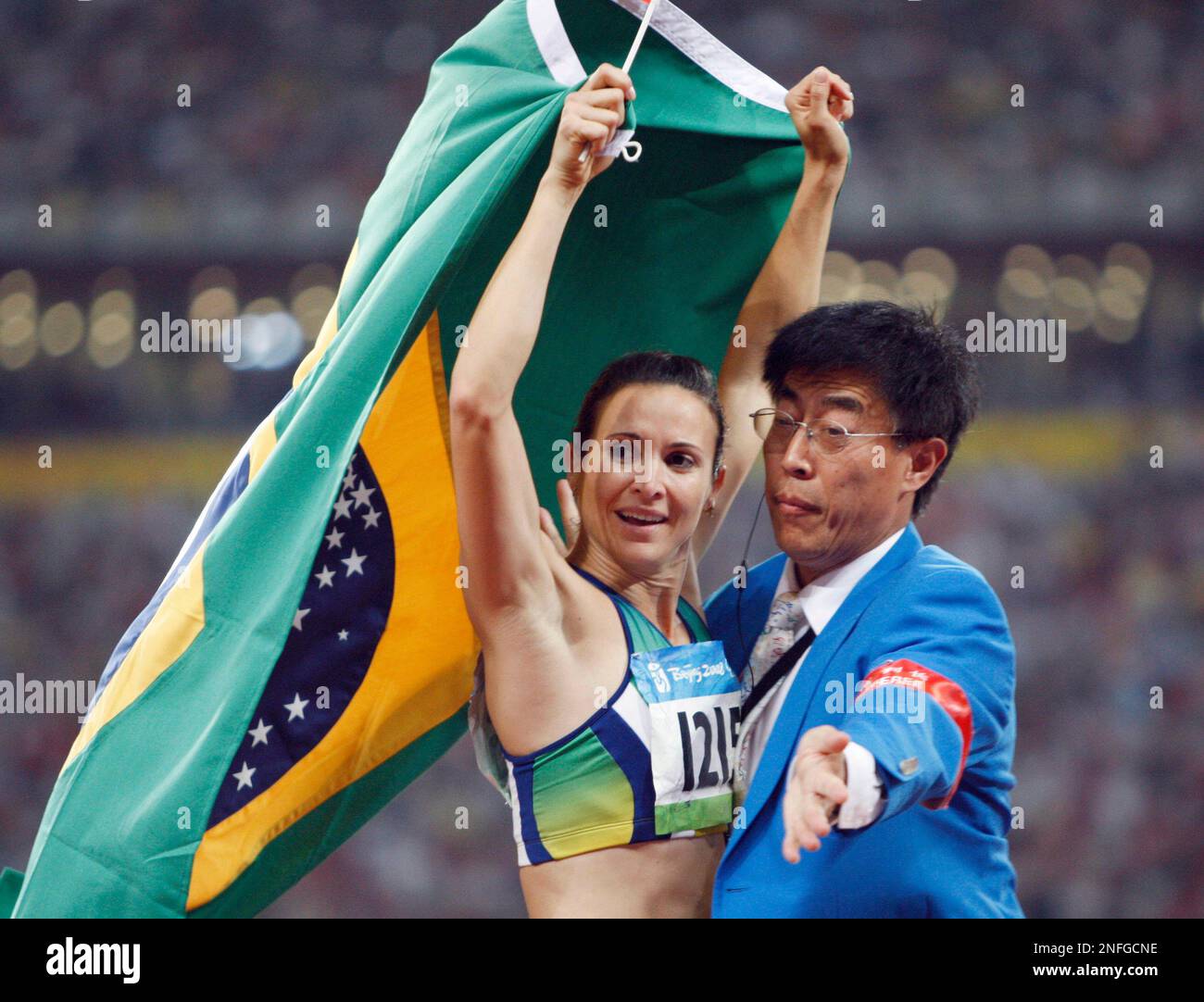A Chinese official guides Brazil's Maurren Higa Maggi as she celebrates ...