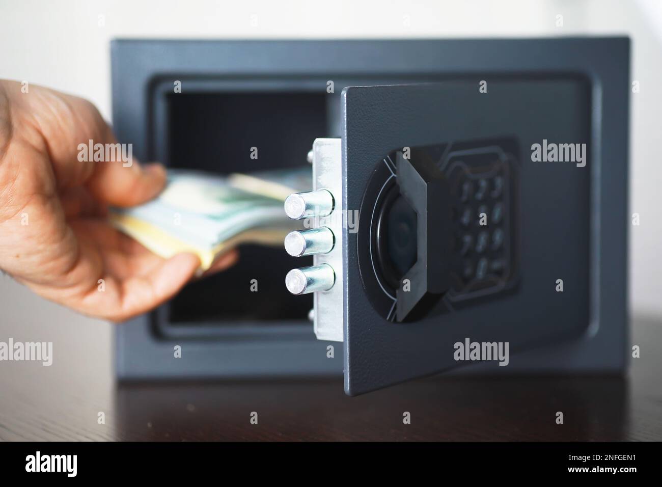 Steel safe with money. Hand putting password in the safety money box in ...