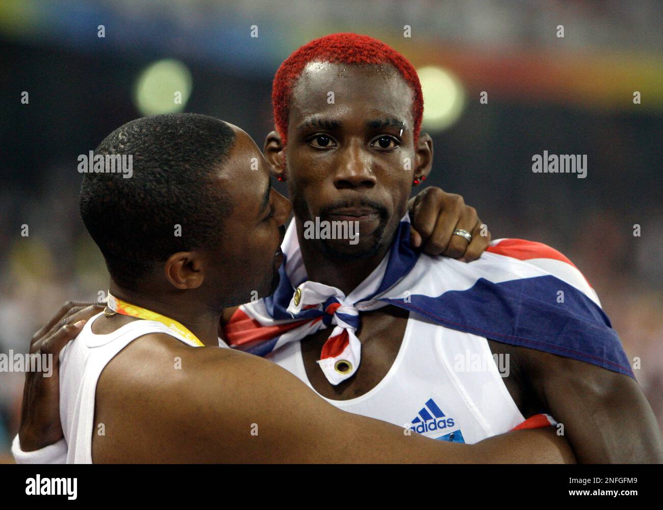 Britain's Phillips Idowu, right, is embraced by former British sprinter ...
