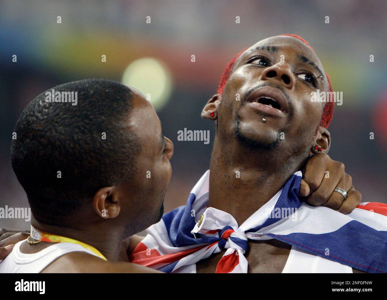 Britain's Phillips Idowu, right, is embraced by former sprinter Darren ...