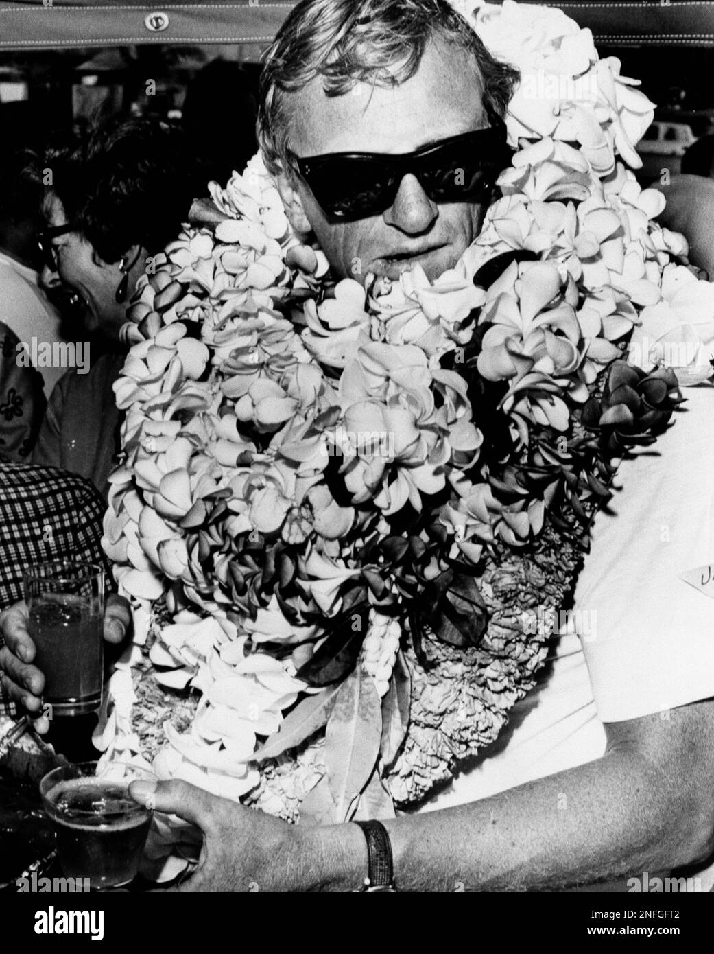 Actor James Arness peers over a collar of Leis he received after he ...