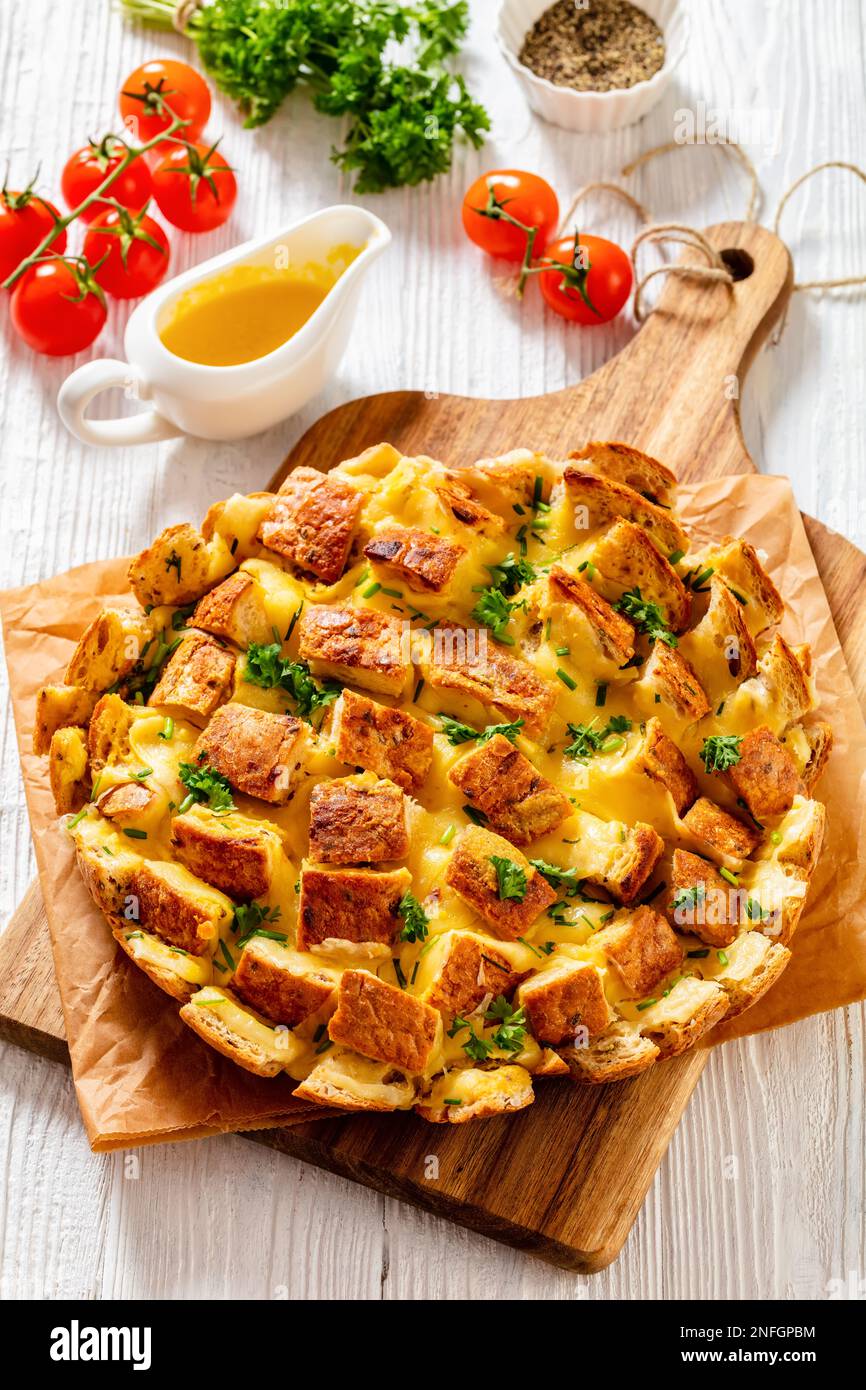 cheesy garlic bread, pull apart whole round bread on cutting board on ...