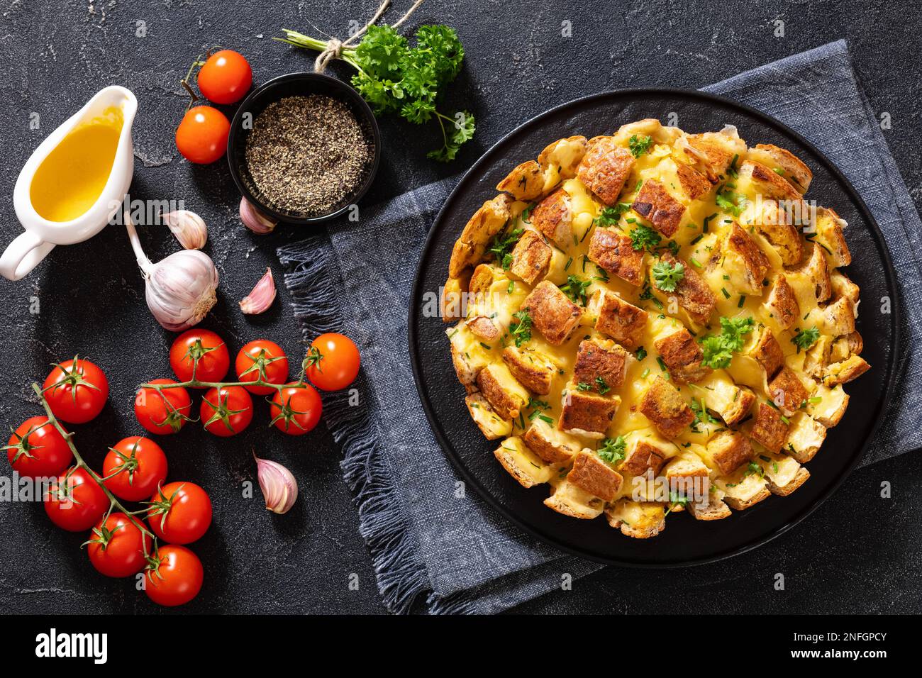 cheesy garlic bread, pull apart whole round bread on black platter on ...