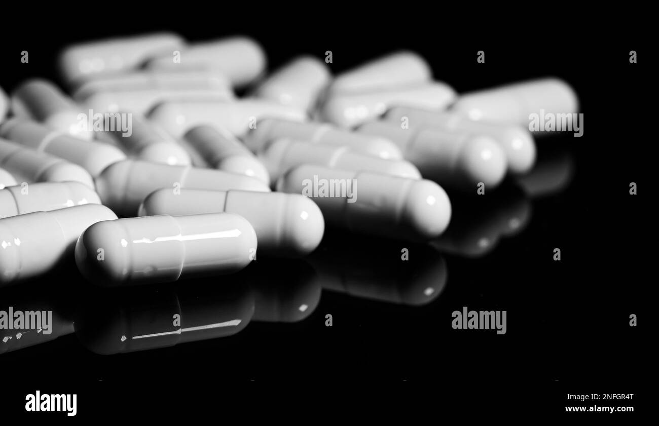Macro Close up of white painkiller capsule on a reflective black ...