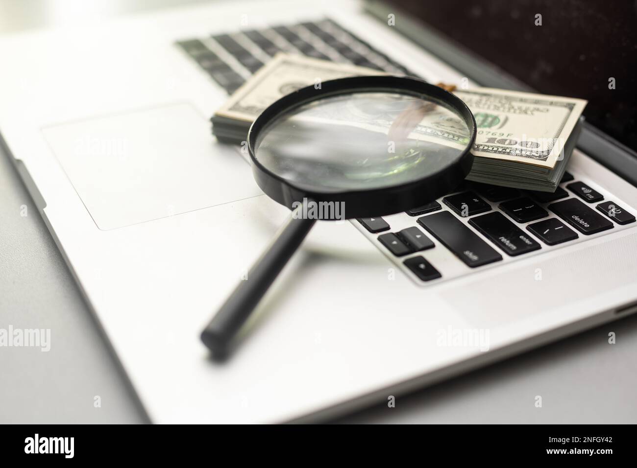 Magnifying glass and dollar bills on laptop. Search for financial ...