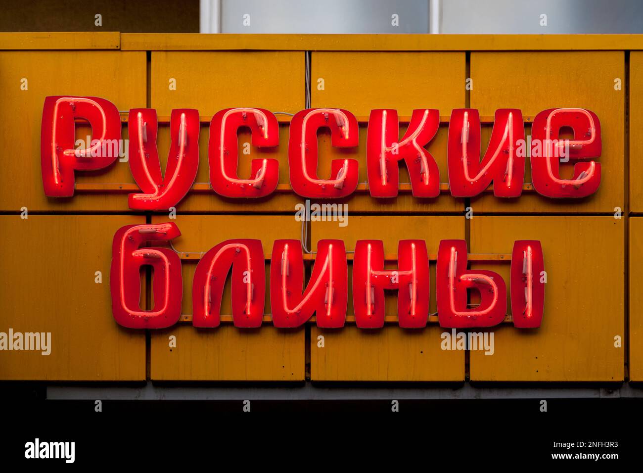 Close-up on a red neon light shaped into the Russian short phrase ...