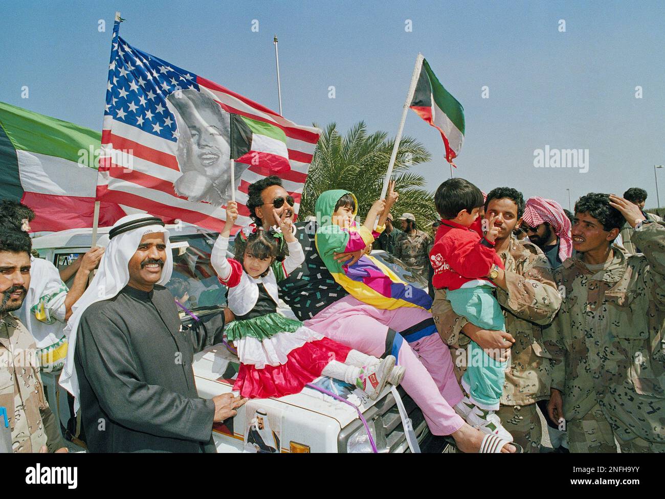 Kuwaitis parade in front of the reopened U. S. embassy waving Kuwaiti ...