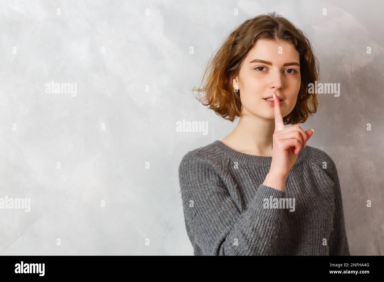 Pretty girl making silence gesture over grey background Stock Photo - Alamy