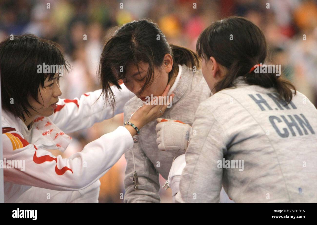 China's Tan Xue, center, is comforted by her teammates Huang Haiyang ...