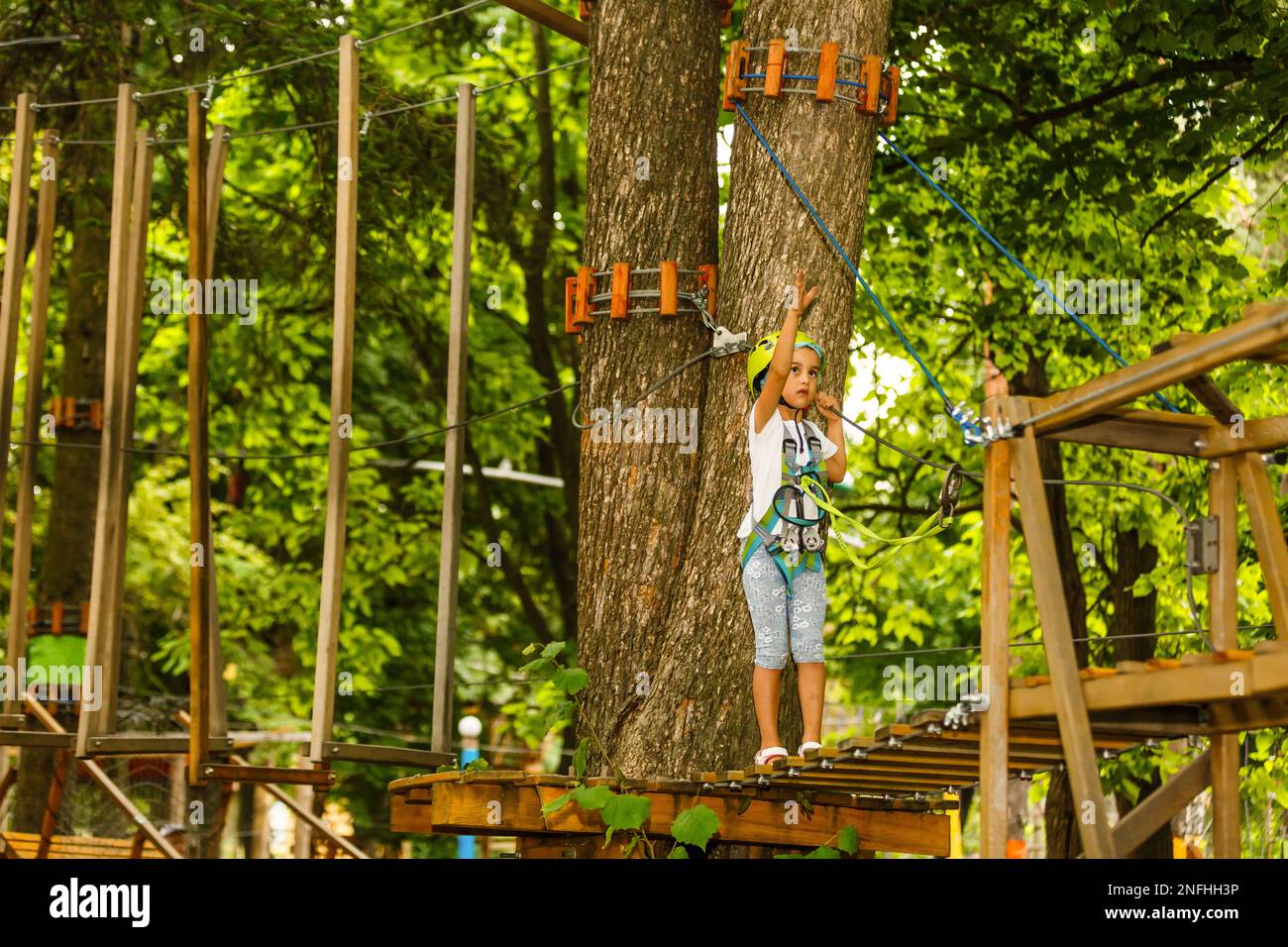Adorable little girl enjoying her time in climbing adventure park on ...