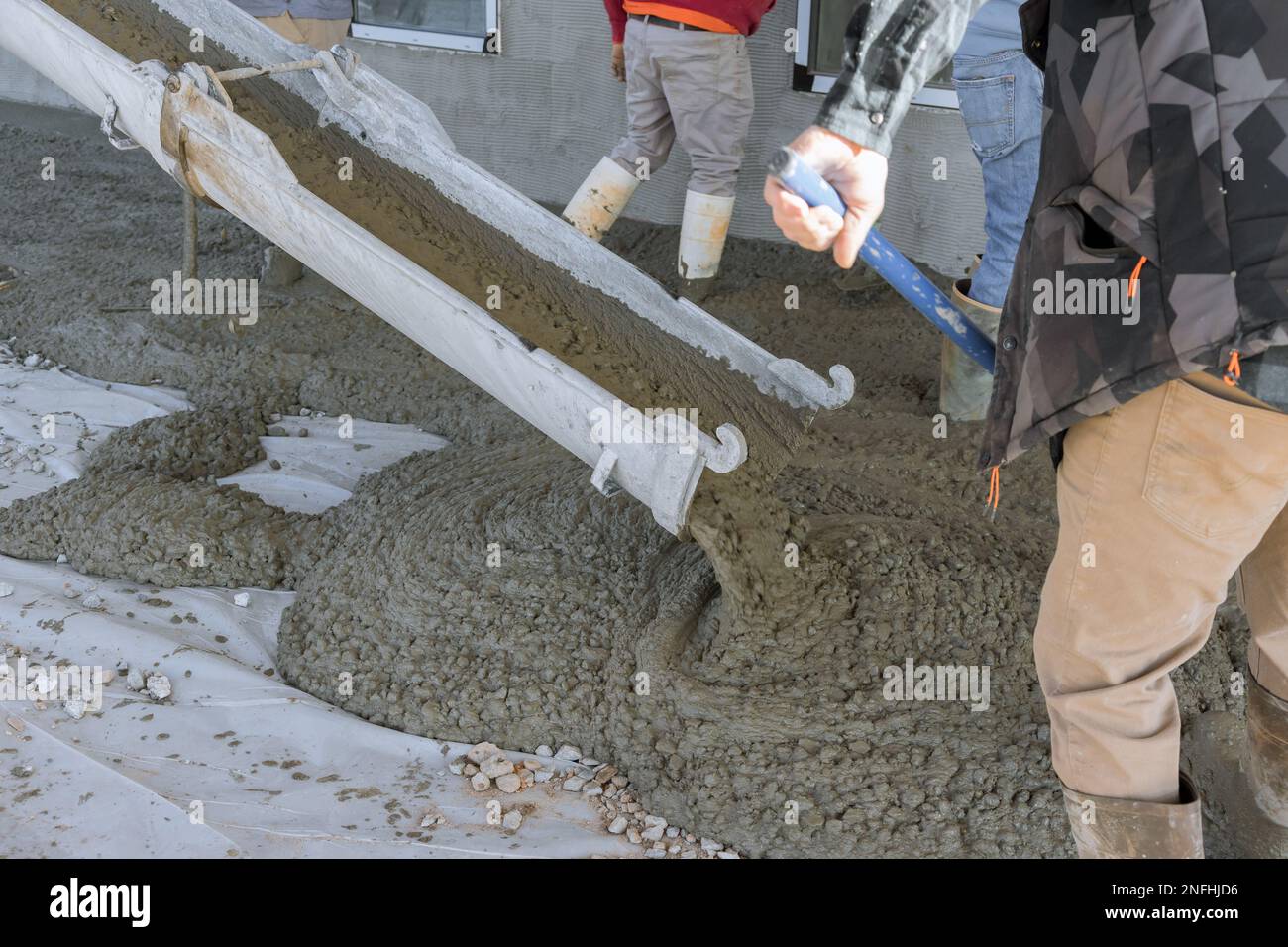 Concrete is being poured from concrete mixing truck around new house to ...