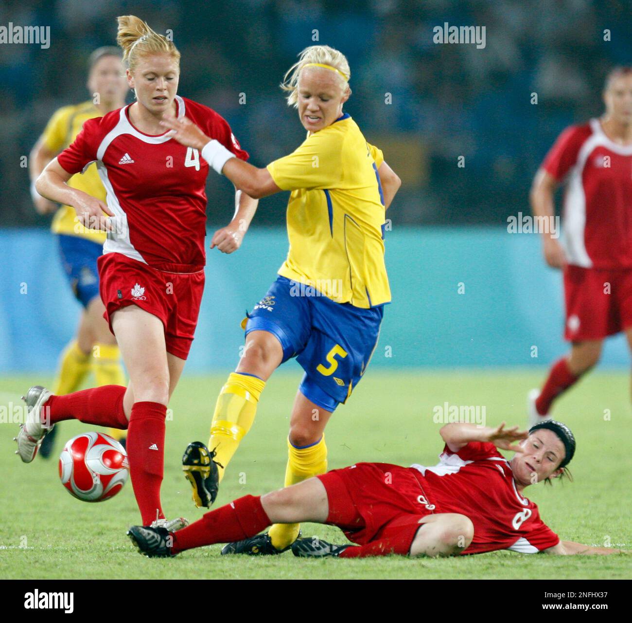 Sweden's Caroline Seger, center is tacled by Canada's Diana Mathenson ...