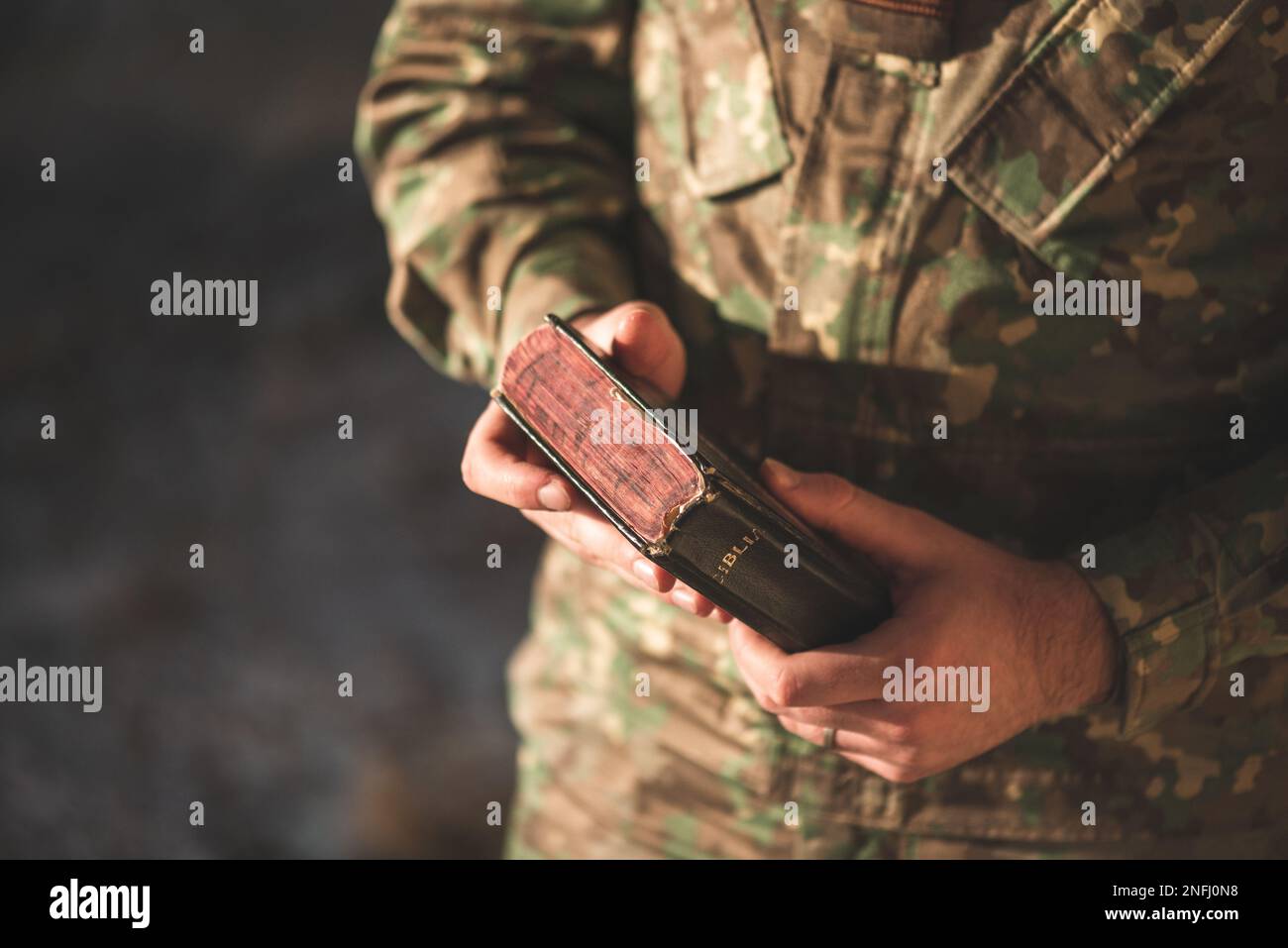 Soldier dressed in camouflage uniform holding a bible in his hand ...