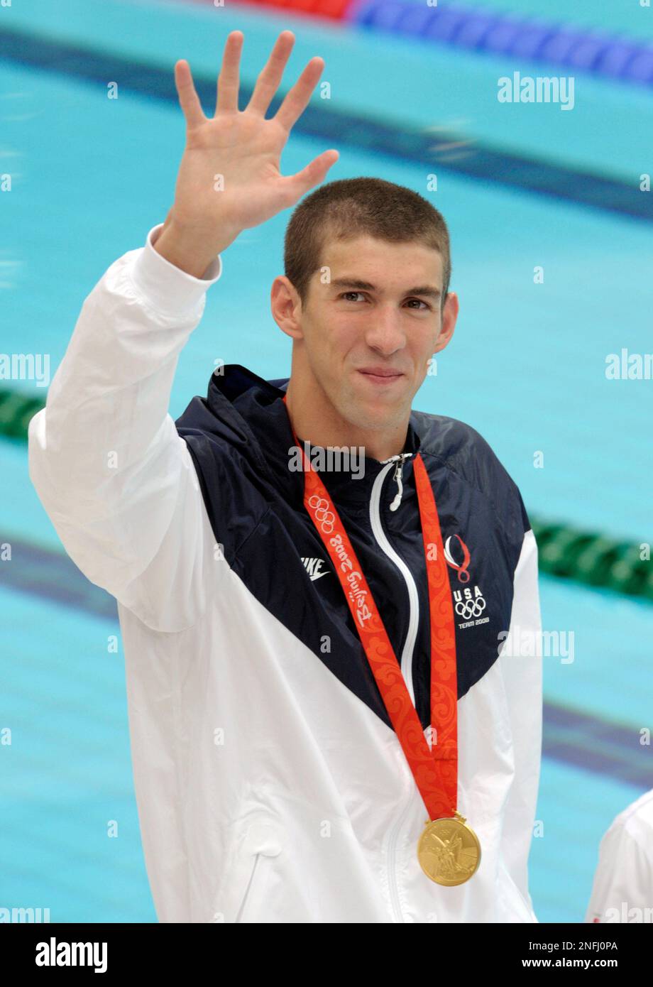 Michael Phelps of the United States waves with the gold medal following ...
