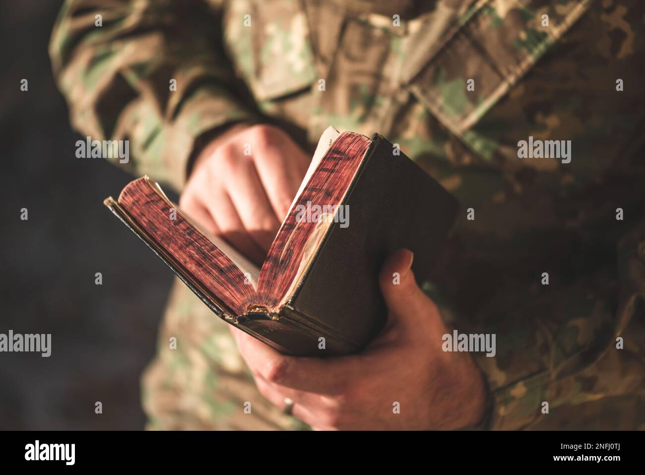 Soldier dressed in camouflage uniform holding a bible in his hand ...