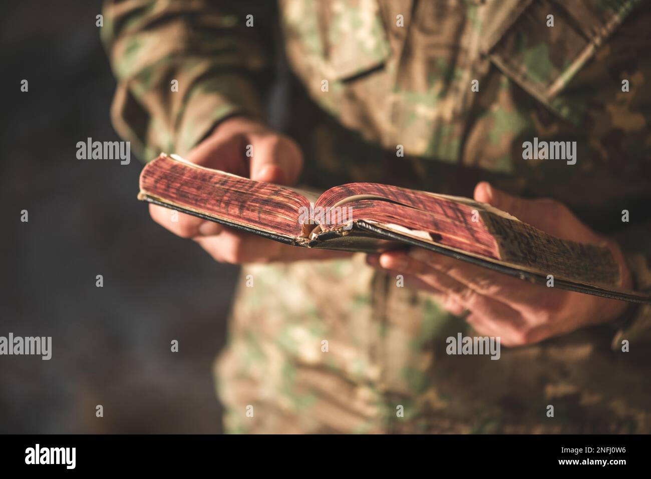 Soldier dressed in camouflage uniform holding a bible in his hand ...