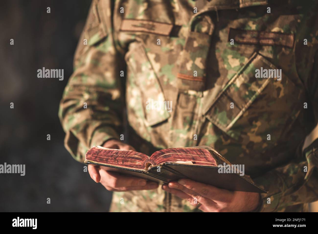 Soldier dressed in camouflage uniform holding a bible in his hand ...