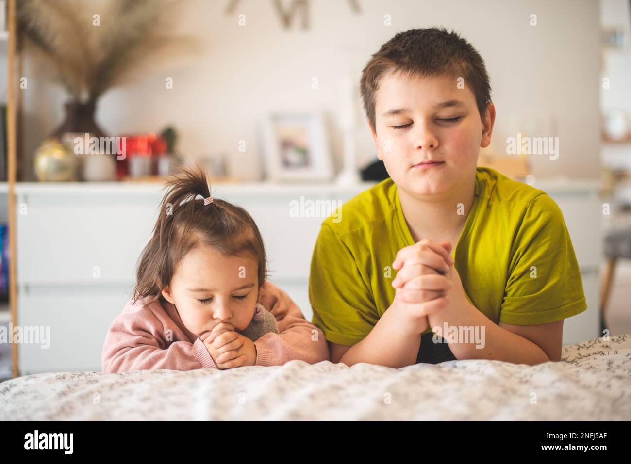 brother and sister praying together in the morning at the edge of the ...