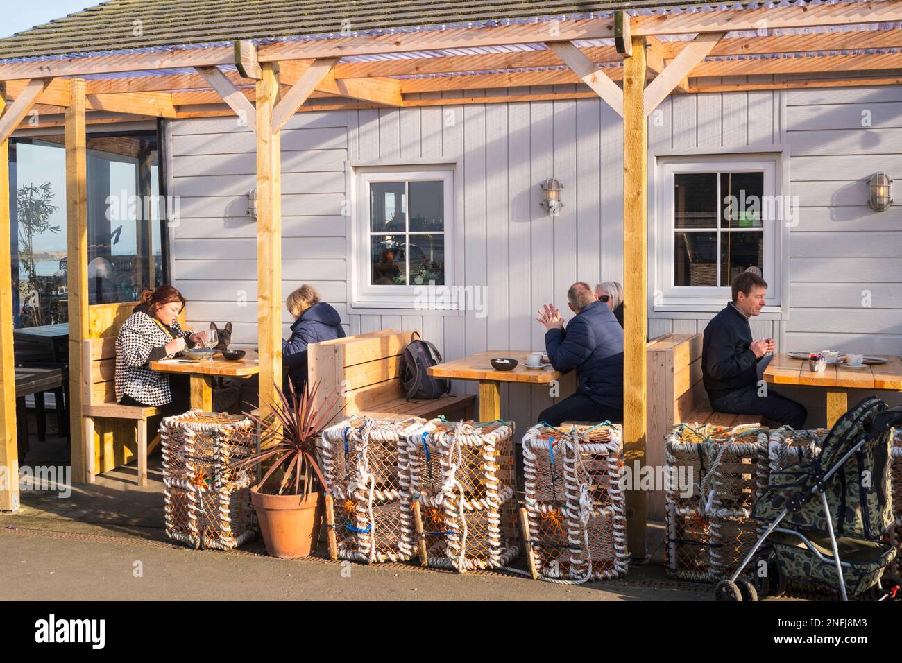 People sitting outside a café in Amble, Northumberland, England, UK ...