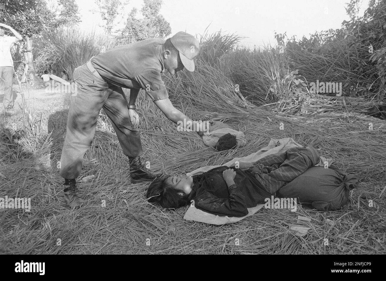 A Thai soldier waves away flies from the face of a sick Cambodian ...