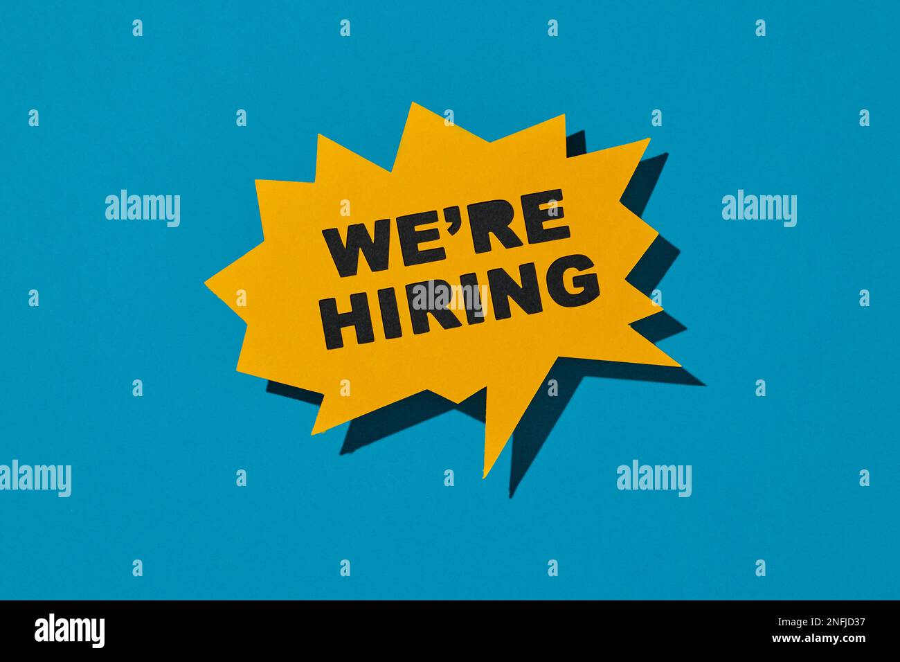 a yellow sign in the shape of a speech bubble reads we are hiring on a ...