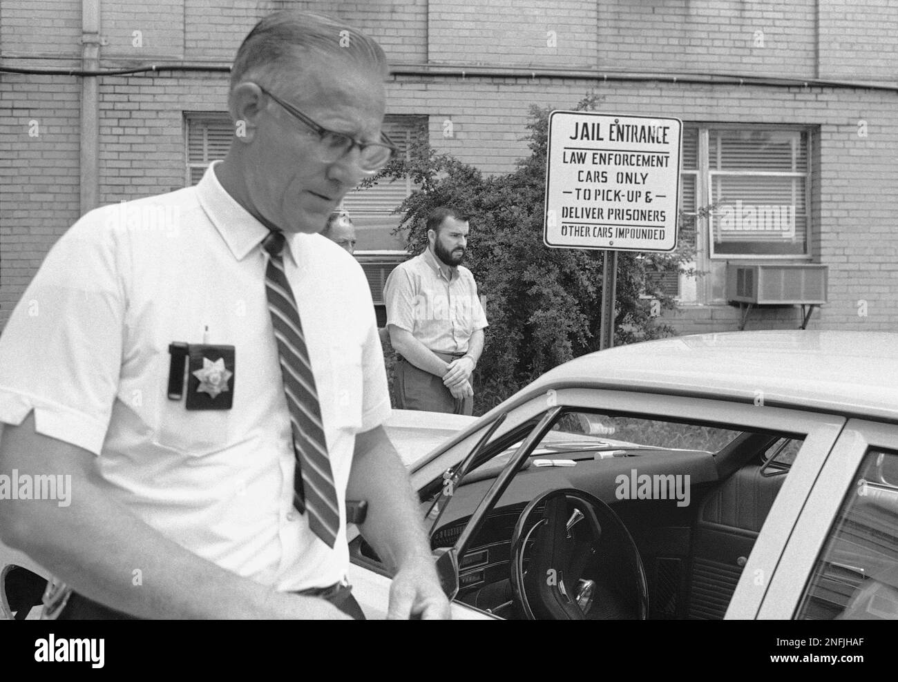 Gary Steven Krist, bearded and handcuffed, in background, is shown ...