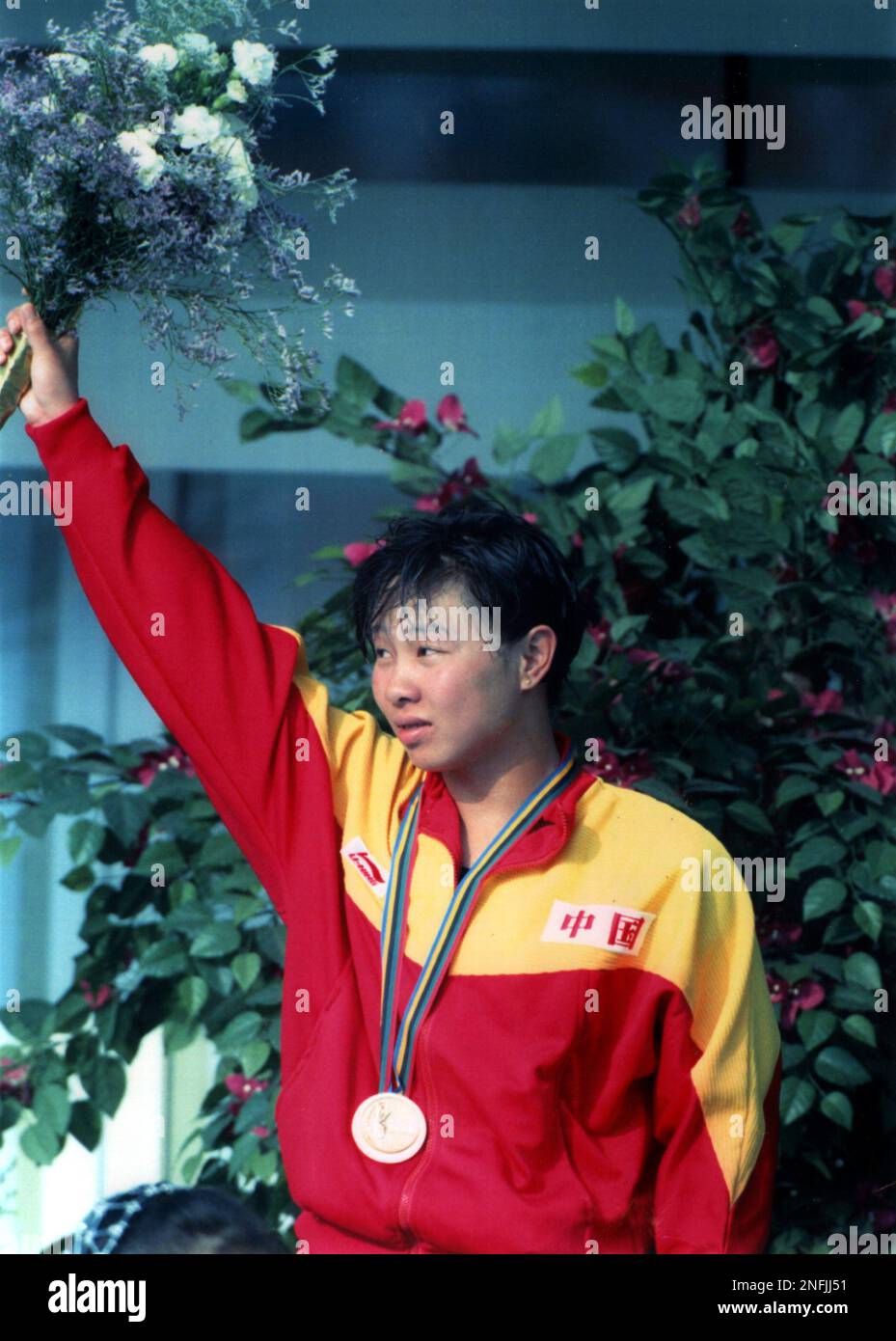 China's Qian Hong waves a bunch of flowers as she displays the gold ...