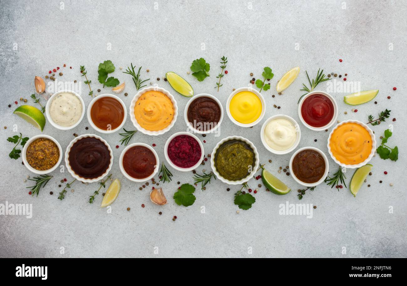 Different types of sauces in bowls with seasonings, rosemary and pepper ...