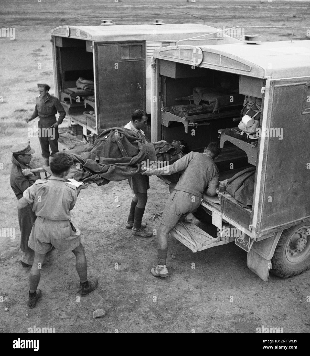 Stretcher bearers slide a stretcher bearing a wounded British Soldier ...