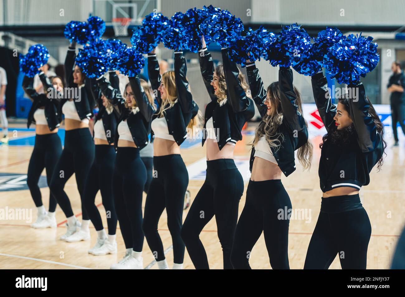 pretty cheerleaders in black pants and jackets and white tops holding ...