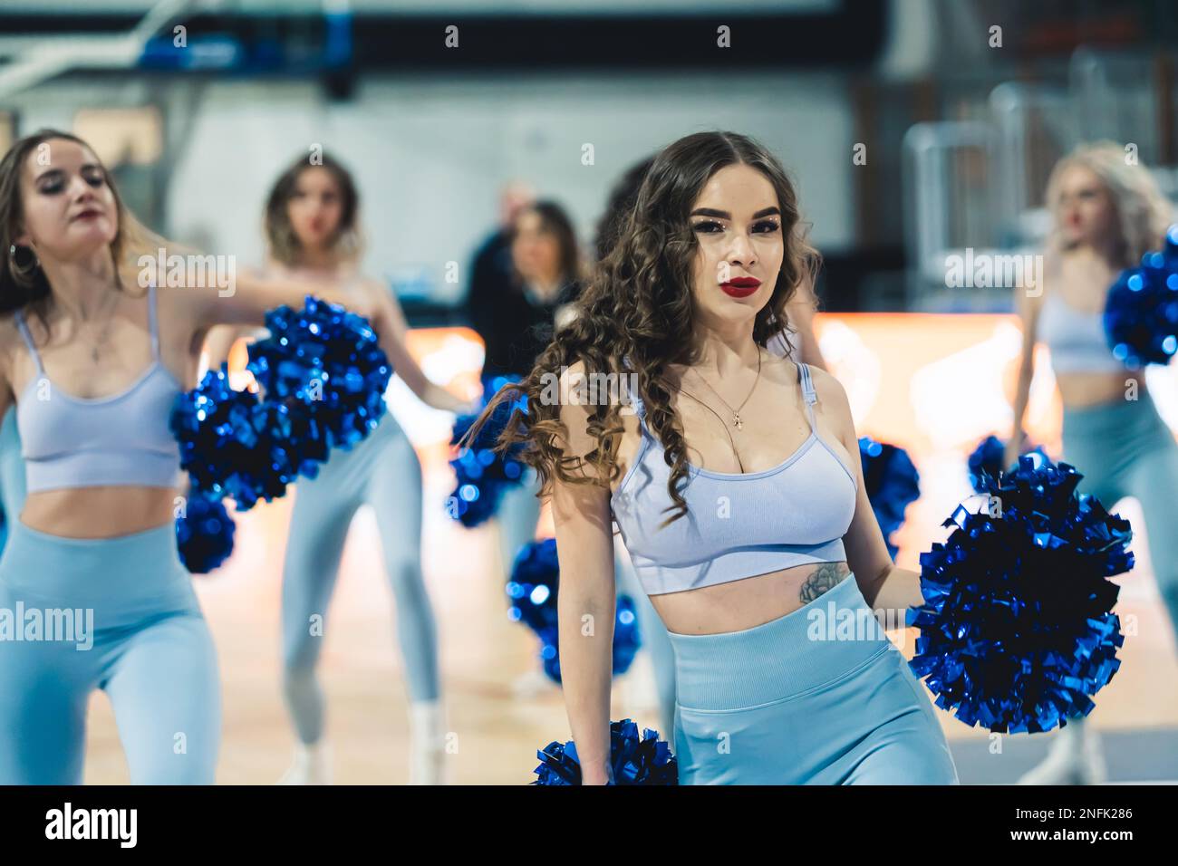 cheerleaders in light blue uniforms practicing in the arena, medium ...