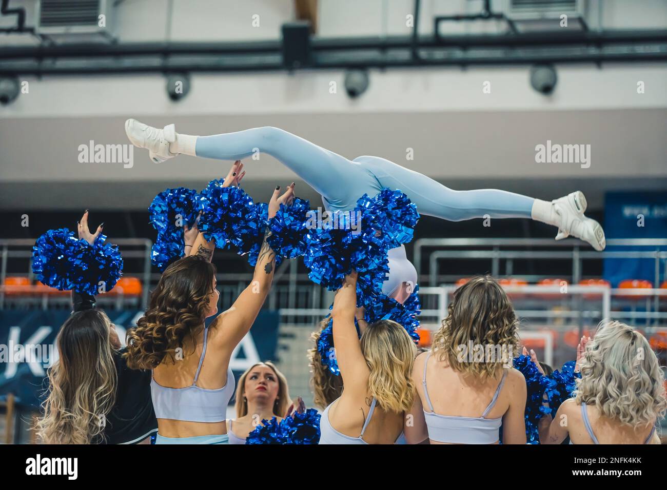 cheerleaders holding a girl up doing a split in the air, indoors. High ...