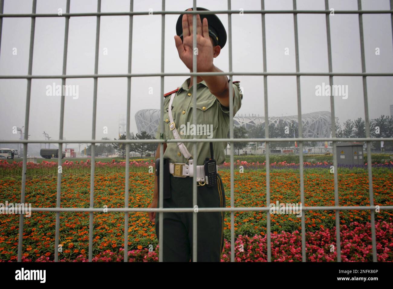 A Chinese security guard gestures while asking not to take his photo as ...