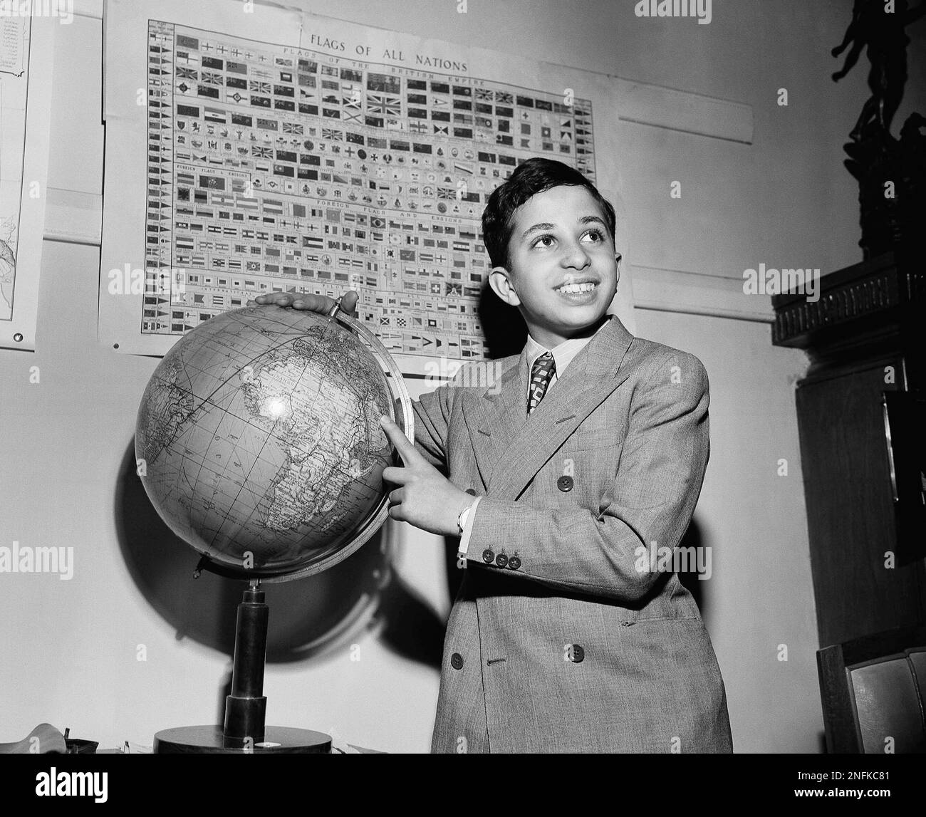 Young King Faisal II of Iraq points to his country on a globe, in ...
