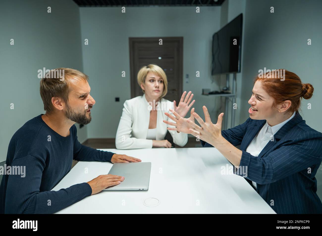 Blond, red-haired woman and bearded man in suits in the office ...