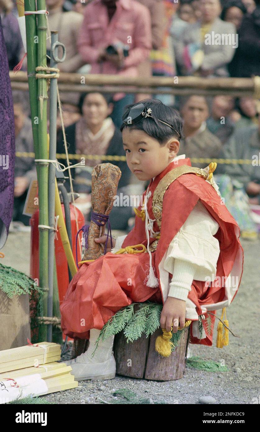 An 11 year old boy, wearing a traditional priest costume watches the ...
