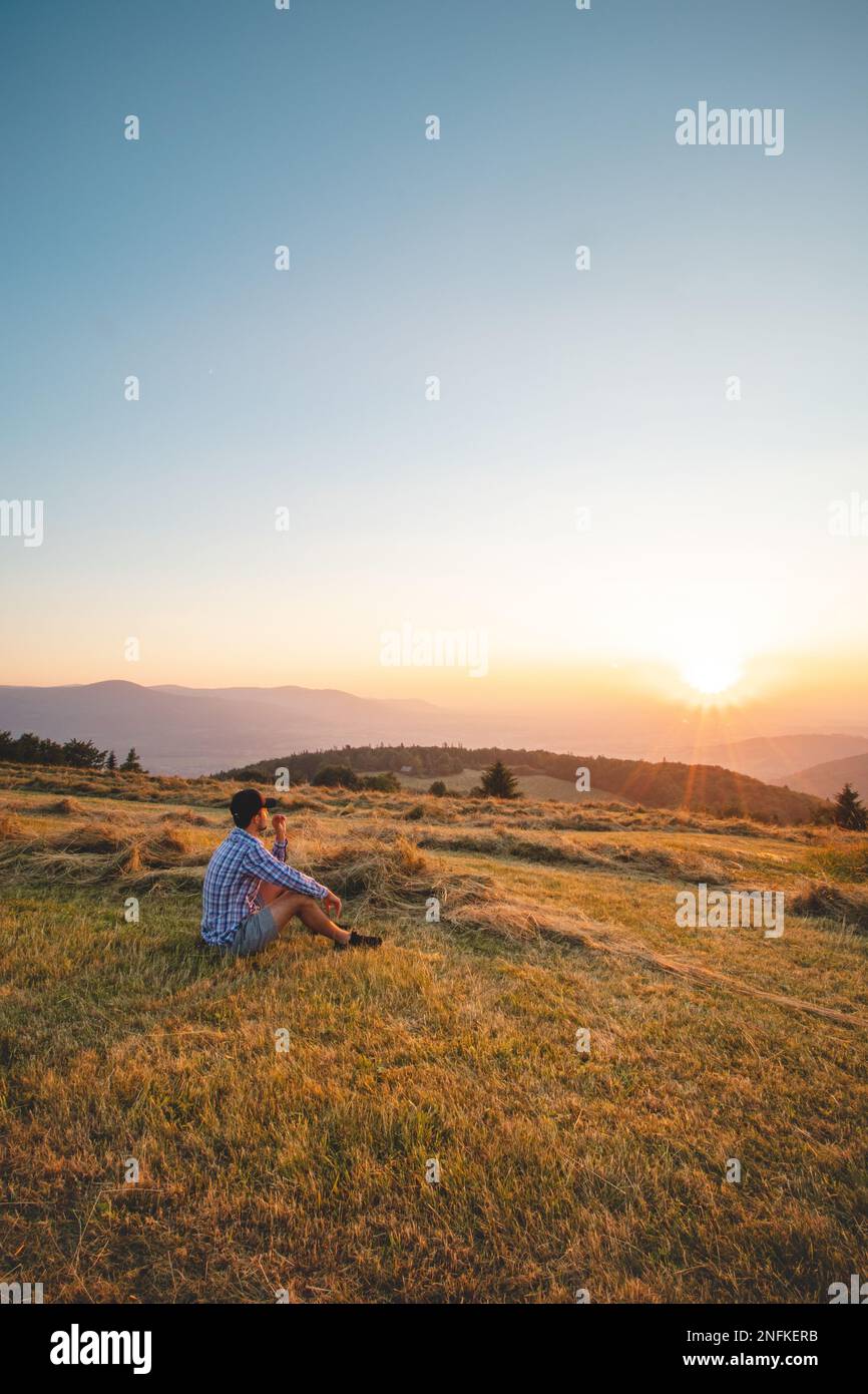 Man sitting by a haystack relaxes and lets the stress leave his body as ...