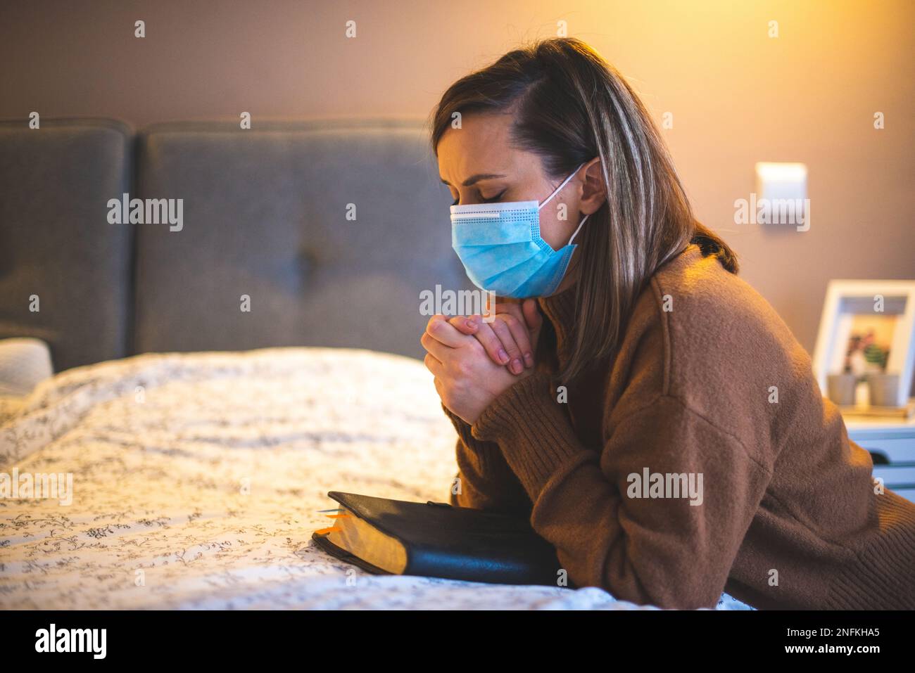 Woman with mask praying next to bed with her bible near Stock Photo - Alamy