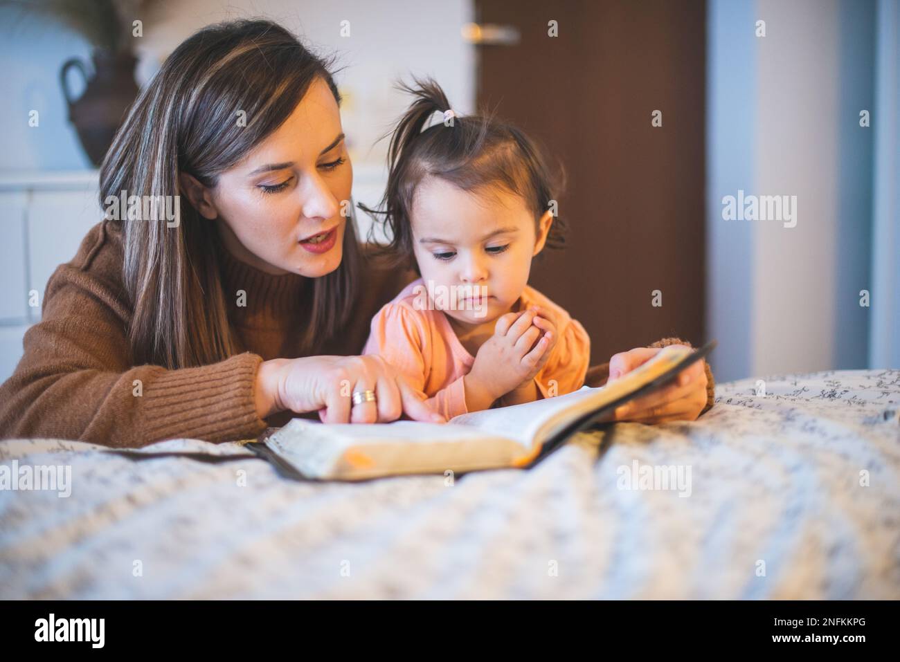 mother and her little girl praying at the edge of the bed in the ...