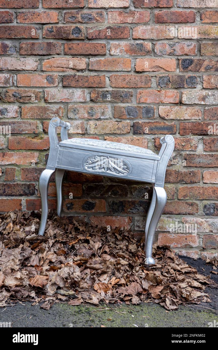 Abandoned silver stool against a red brick wall Stock Photo - Alamy