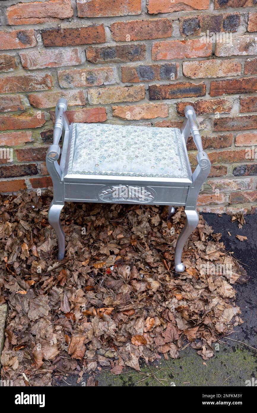 Abandoned silver stool against a red brick wall Stock Photo - Alamy